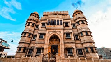 Um edifício grande e ornamentado com uma entrada em arco central e várias varandas.