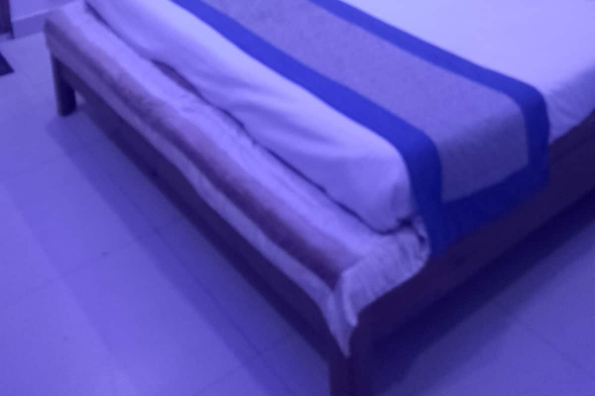Um quarto com cama, mesa de cabeceira e guarda-roupa.