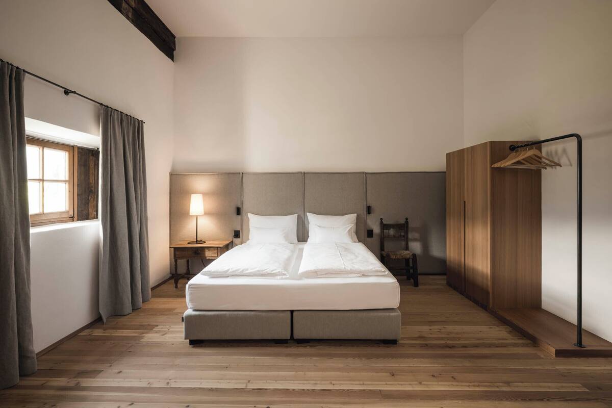 Quarto com cama, mesa de cabeceira, luminária e guarda-roupa.