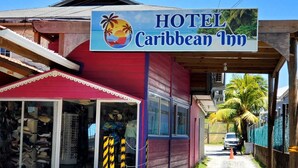 Um hotel chamado Caribbean Inn com uma placa mostrando um pôr do sol e palmeiras.