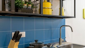 Uma cozinha com azulejos azuis, uma pia, um bloco de facas e panelas no balcão.