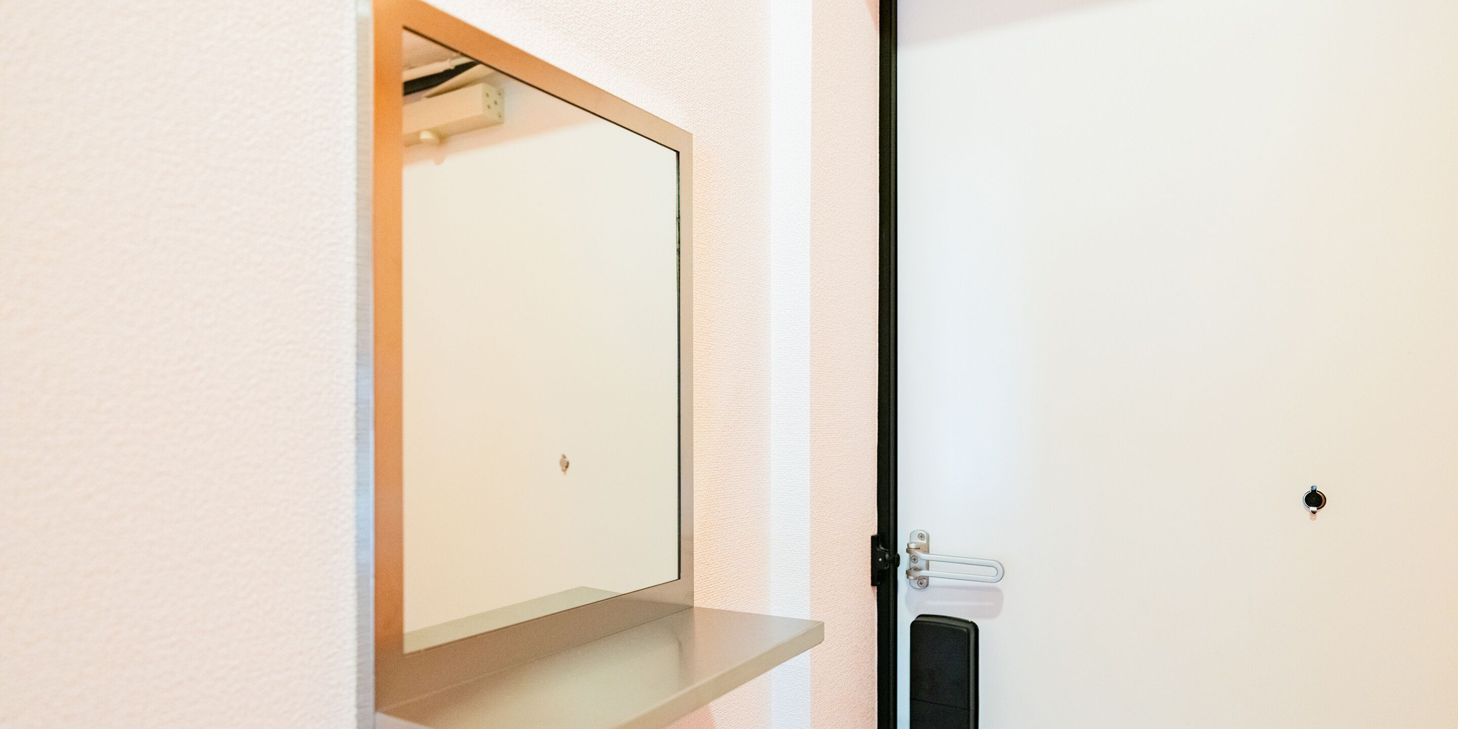 Uma porta com puxador preto e um pequeno orifício na parede.