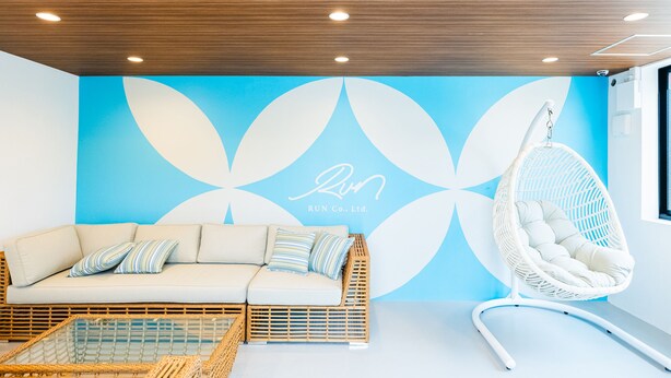 Uma sala de estar moderna com um sofá, uma cadeira suspensa e uma parede com um logotipo grande.