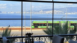 Uma área de refeições com vista para o mar e um ônibus verde ao fundo.