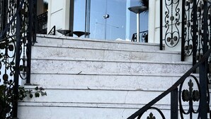 Uma escadaria com grades de metal preto ornamentadas e paredes brancas.