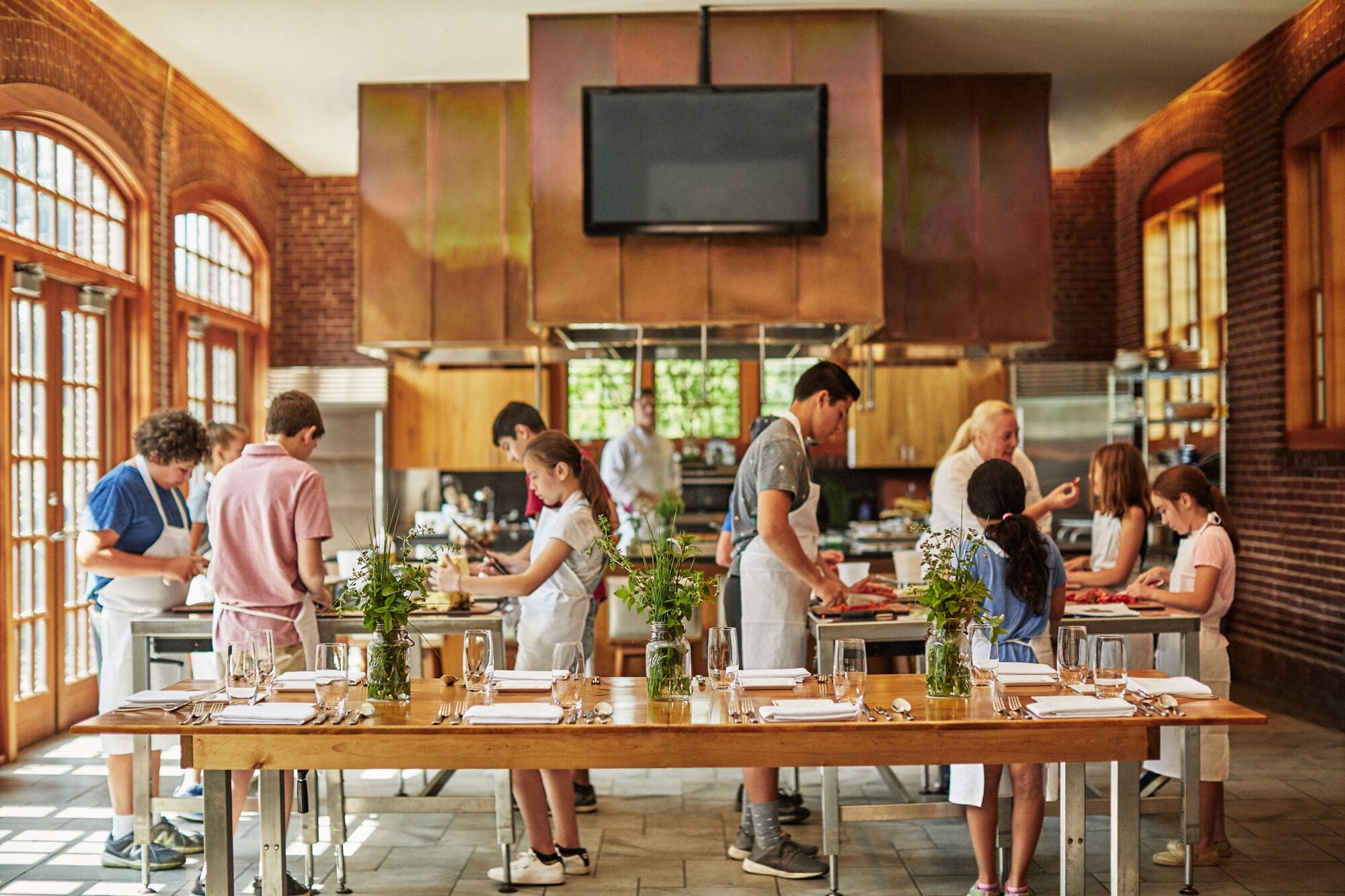 Um restaurante amplo com tetos de madeira alta, grandes janelas e uma área de cozinha central.