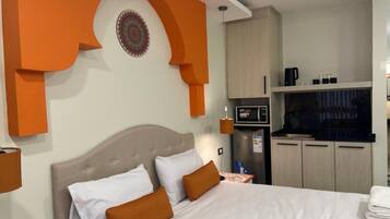 Quarto de hotel com cama, micro-ondas, frigorífico e televisão.