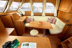 Um interior acolhedor com mesa de madeira, assentos estofados e vista pela janela.
