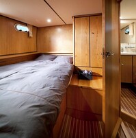 Uma cabana compacta com uma cama de solteiro, uma pequena janela e um guarda-roupa de madeira.