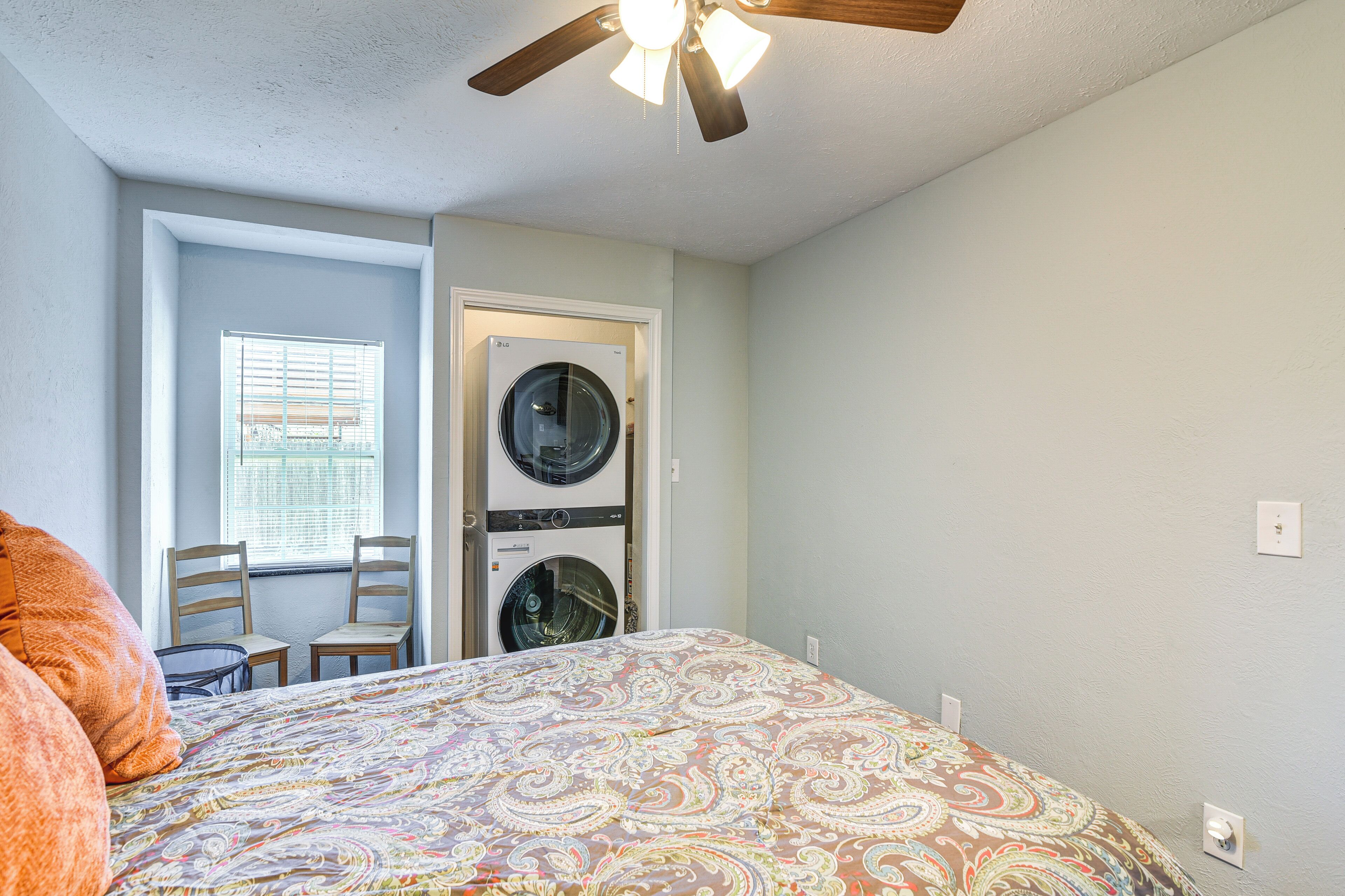 Quarto com cama, ventilador de teto, máquina de lavar e janela com persianas.