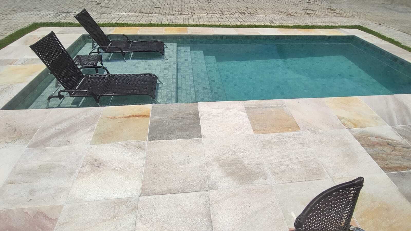Piscina com deck revestido e espreguiçadeiras.