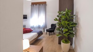 Quarto moderno com cama, uma cadeira, planta em vaso e janela com cortinas.