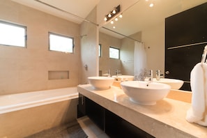 Uma casa de banho moderna com uma banheira grande, duas pias e um espelho amplo.
