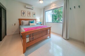Quarto com cama de madeira, janela com cortinas e ar-condicionado fixado na parede.