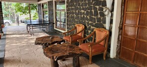Um quarto com paredes de pedra, uma mesa de pingue-pongue, cadeiras de madeira e uma mesa de centro rústica de madeira.