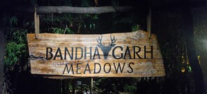Uma placa de madeira rústica com o texto 'Bandha Garh Meadows' e um símbolo de veado.