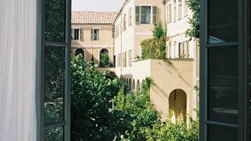Um pátio com edifícios com janelas em arco e varandas, cercado por vegetação.
