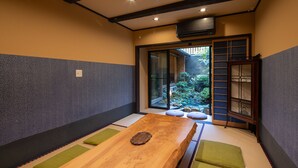 Um quarto japonês tradicional com tatame, uma mesa de madeira e uma porta deslizante para um jardim.