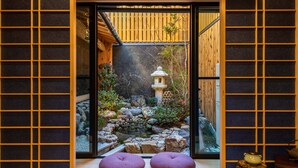 Um jardim japonês tradicional com um lago de carpas, pedras e um farol.