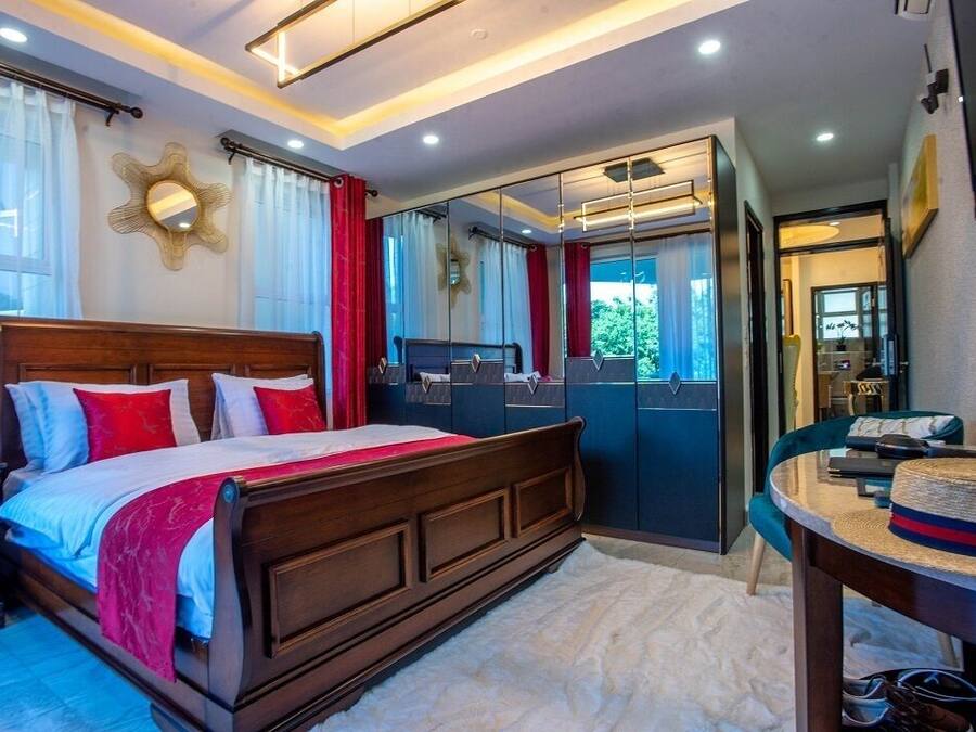 Quarto com cama de madeira, espelho, penteadeira e vista para o exterior.