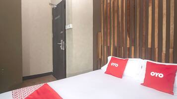 Quarto de hotel com uma cama, cabeceira de madeira e uma porta.