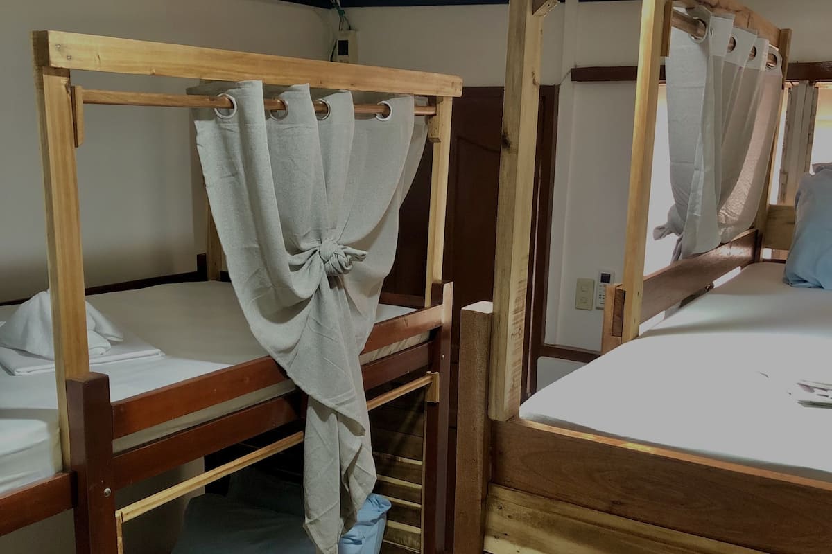 Quarto com duas beliches de madeira, cada uma com colchão e travesseiro.