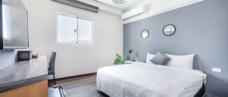 Quarto de hotel moderno com uma cama grande, uma escrivaninha e uma cadeira.