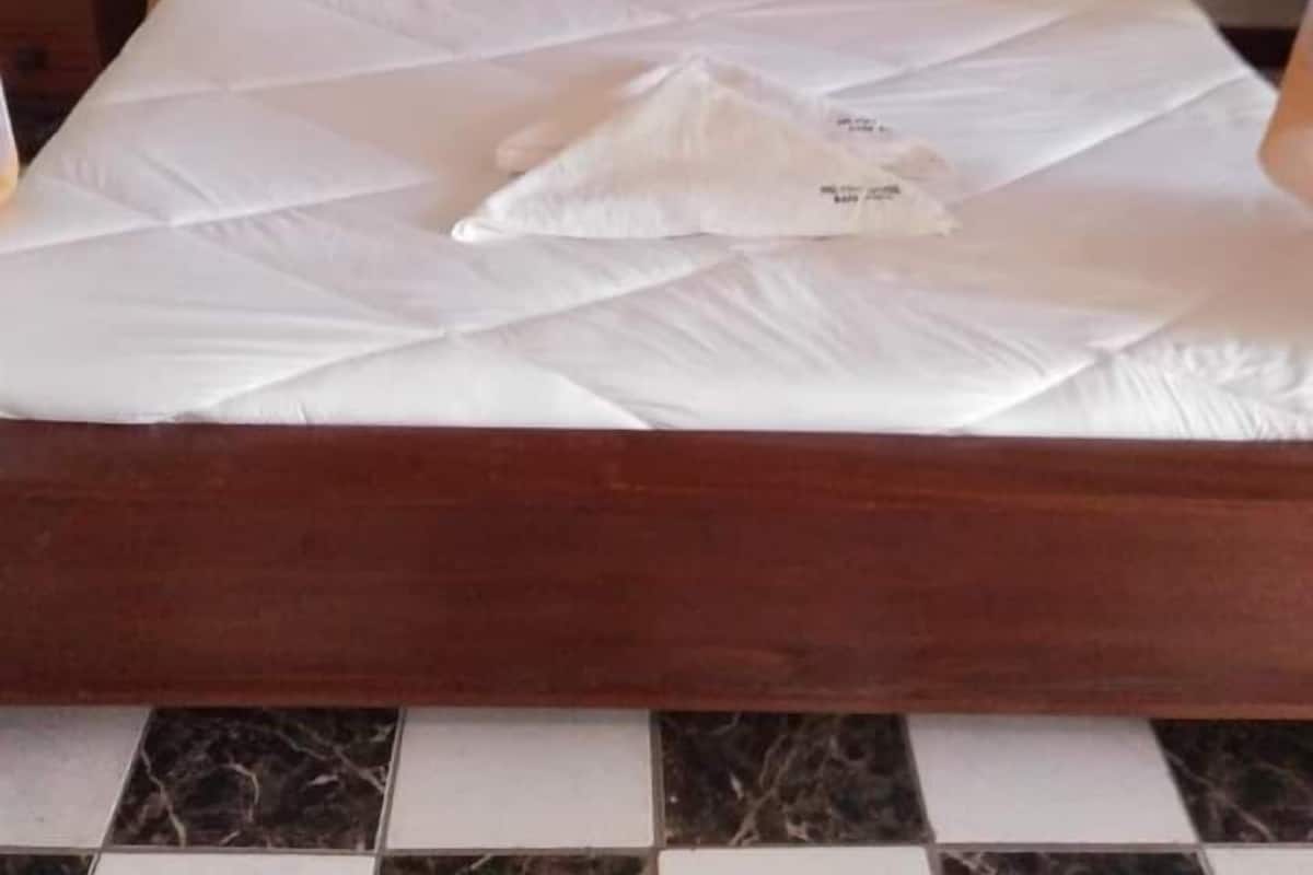 Uma cama com dossel, roupa de cama branca e cabeceira de madeira.
