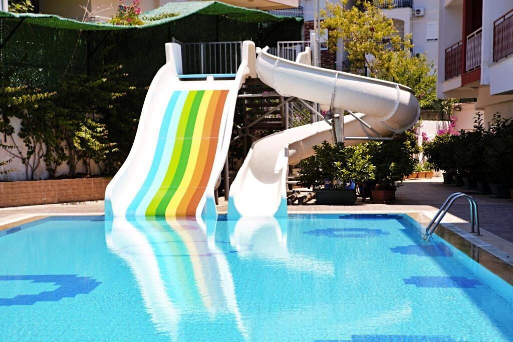 Uma piscina com um escorregador multicolorido e um corrimão de metal.