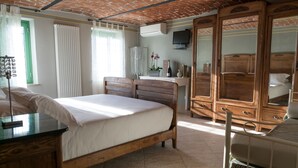 Quarto com cama, penteadeira de madeira e escrivaninha com abajur.