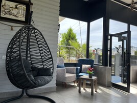 Uma sala de estar moderna com uma cadeira suspensa, uma poltrona azul e uma pequena mesa com um vaso de flores.