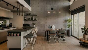 Cozinha moderna com ilha central, banquetas e área de jantar com mesa e cadeiras.