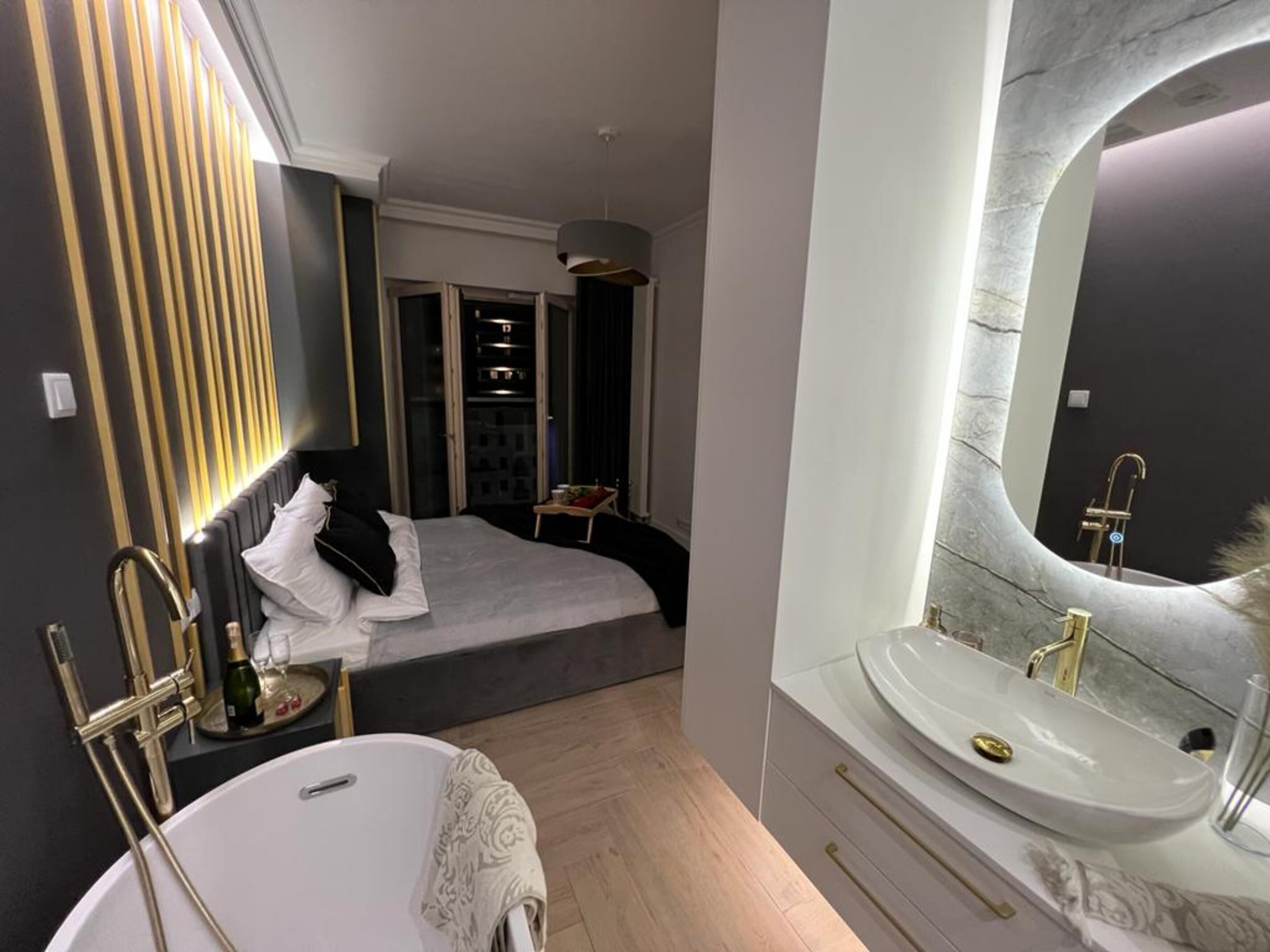 Quarto moderno com uma cama grande, uma penteadeira com espelho e uma banheira.