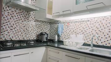 Cozinha com armários brancos, bancada preta e painel de azulejos.