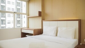Quarto de hotel com cama grande, mesa de cabeceira, escrivaninha e janela com vista para edifícios.