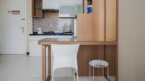 Uma cozinha compacta com bancada de madeira, uma cadeira branca e um banquinho pequeno.