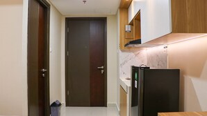 Uma cozinha pequena com geladeira, armários de madeira e painel de backsplash de mármore.