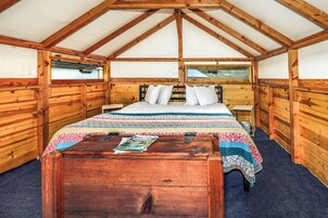 Quarto de cabana de madeira com cama, um baú de madeira e uma janela.