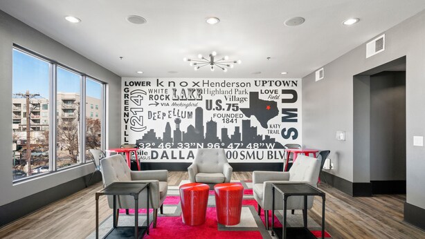 Um hall de hotel moderno com um mural da paisagem urbana, assentos confortáveis e grandes janelas com vista para a cidade.