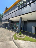 A building with a large sign reading "7-Eleven" and a person standing near caution tape.