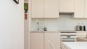 Uma cozinha moderna com armários brancos, uma pia de aço inoxidável e uma cafeteira.