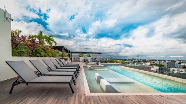 Área de piscina no terraço com espreguiçadeiras e vista para a cidade.