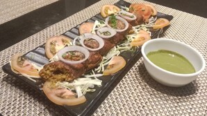 Uma mesa de jantar com um prato de comida, uma tigela de molho e uma caixa de lenços.