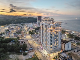 Um hotel alto com vários andares, um estacionamento e vista para o mar.