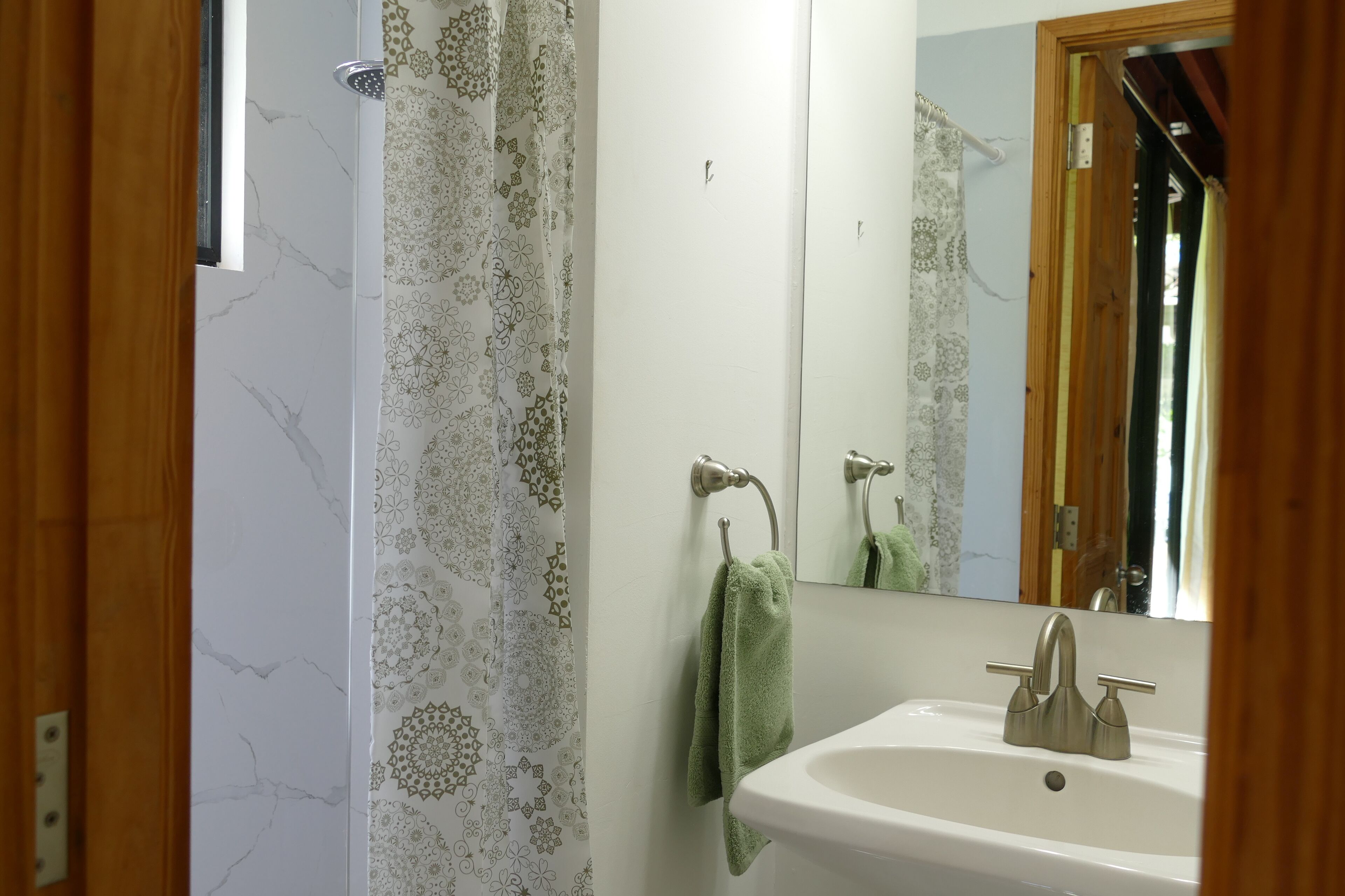 Uma casa de banho com uma pia branca, um espelho e uma cortina de chuveiro com padrão floral.
