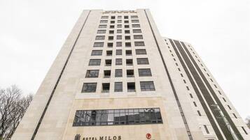 Um prédio alto de hotel com a placa "Hotel Milos" na fachada.