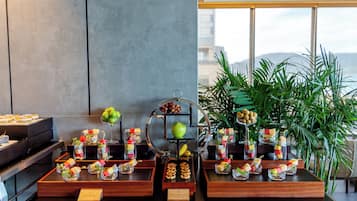 Disposição de buffet com diversos alimentos e um arranjo decorativo.