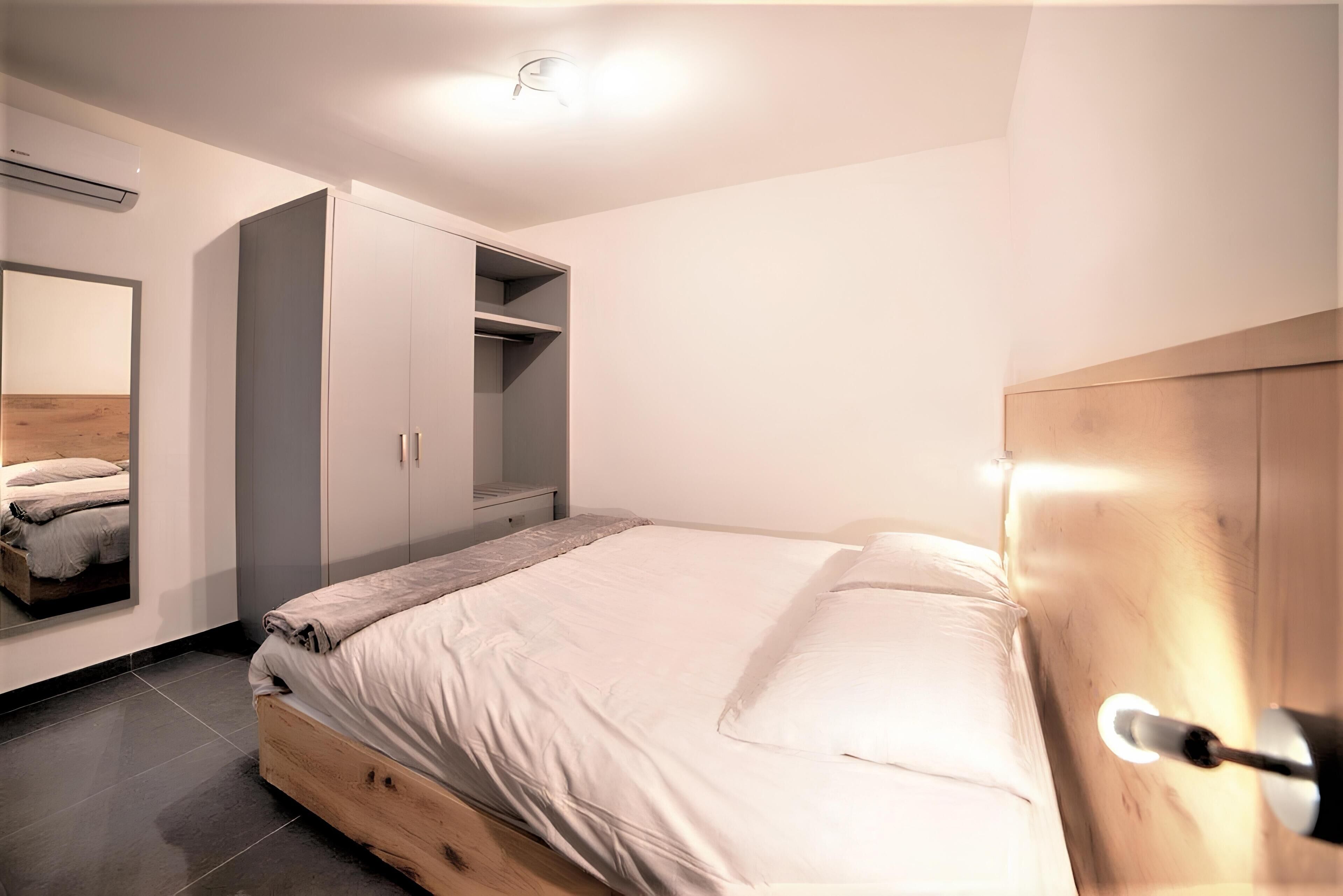 Quarto com cama, guarda-roupa e espelho.