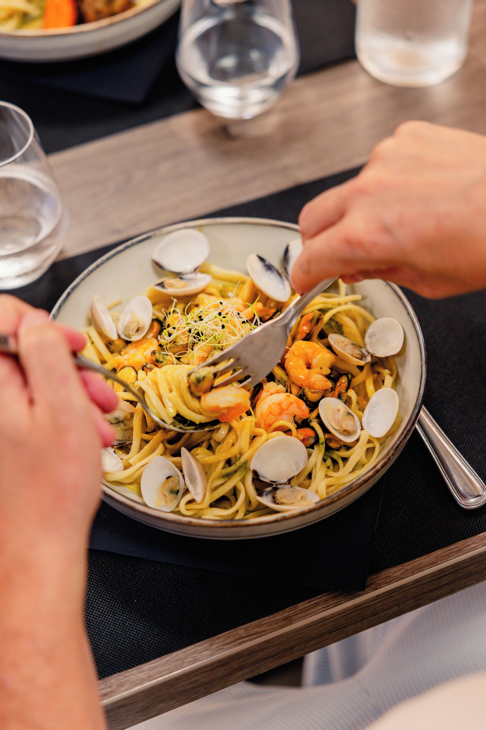 Uma mesa de jantar com um prato de massa, amêijoas e camarões.