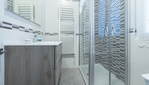 Uma casa de banho moderna com cabine de duche em vidro, toucador de madeira e painel de azulejos.